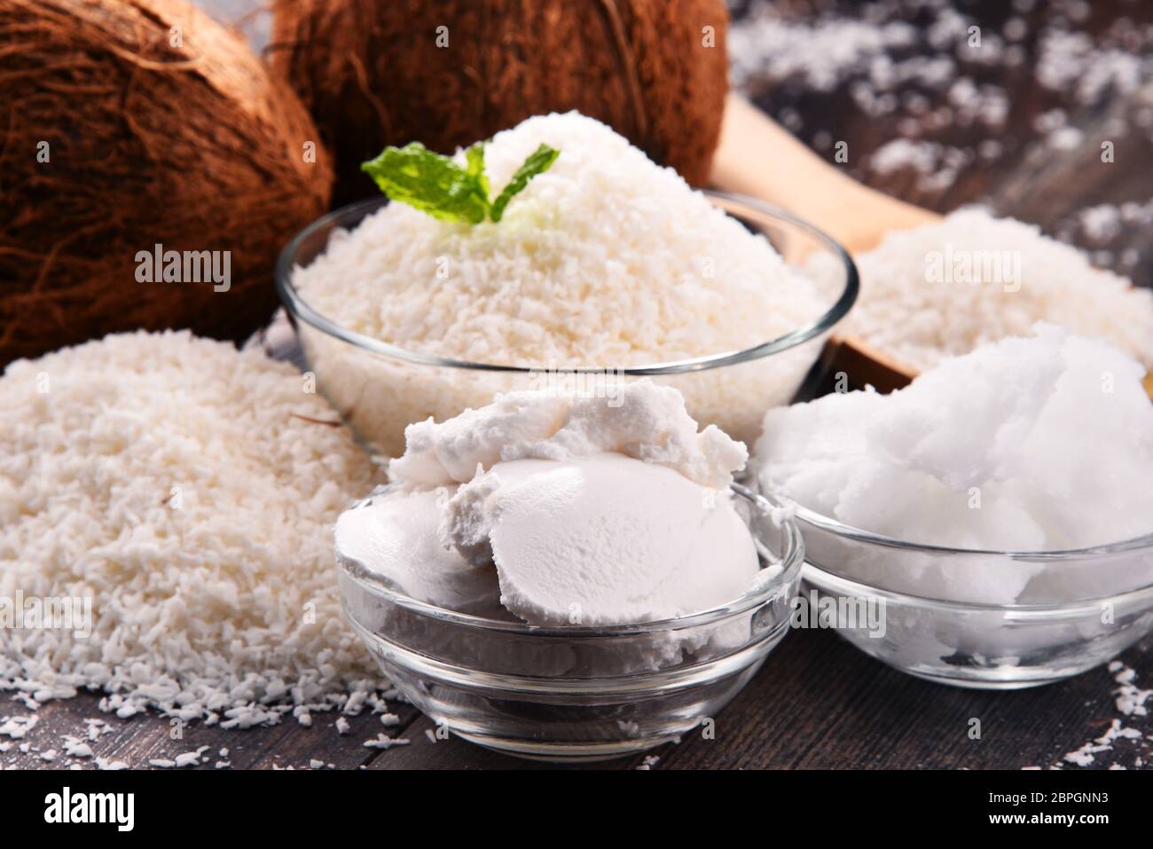Composition with bowl of shredded coconut and shells on wooden table ...
