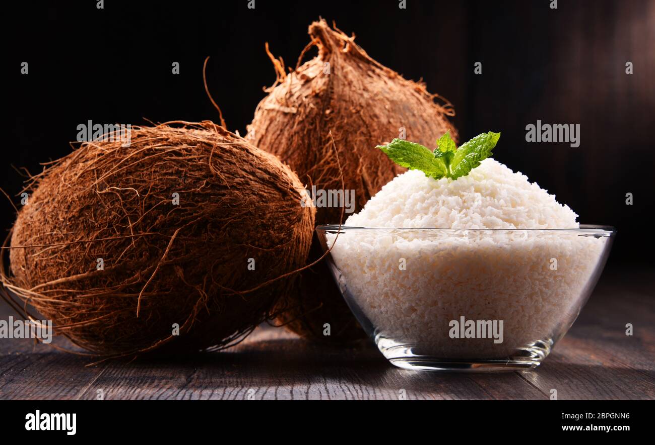 Composition with bowl of shredded coconut and shells on wooden table ...