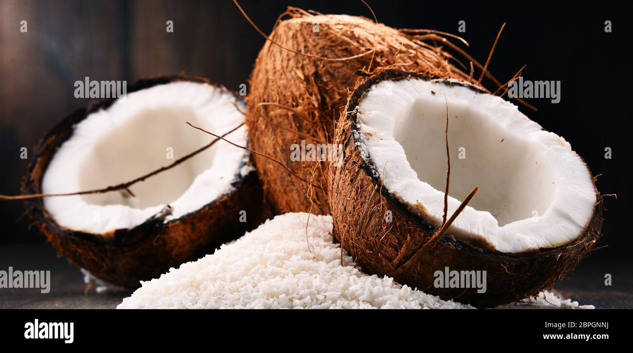 Composition with bowl of shredded coconut and shells on wooden table ...