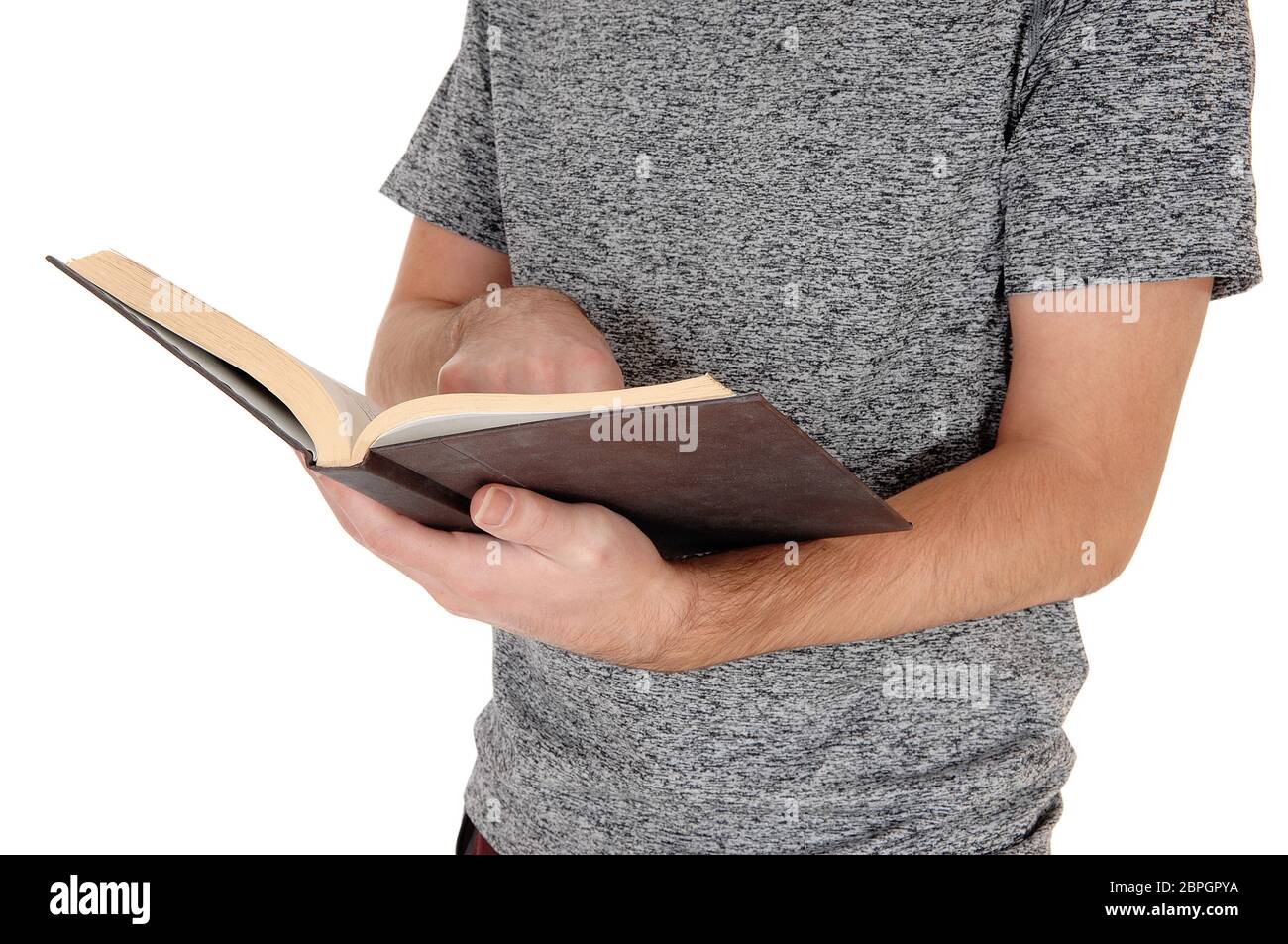 A middle body part of a young man standing and reading his book in a ...