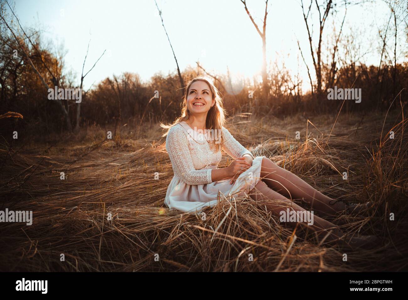 girl is sitting in the field on the sunset background Stock Photo - Alamy