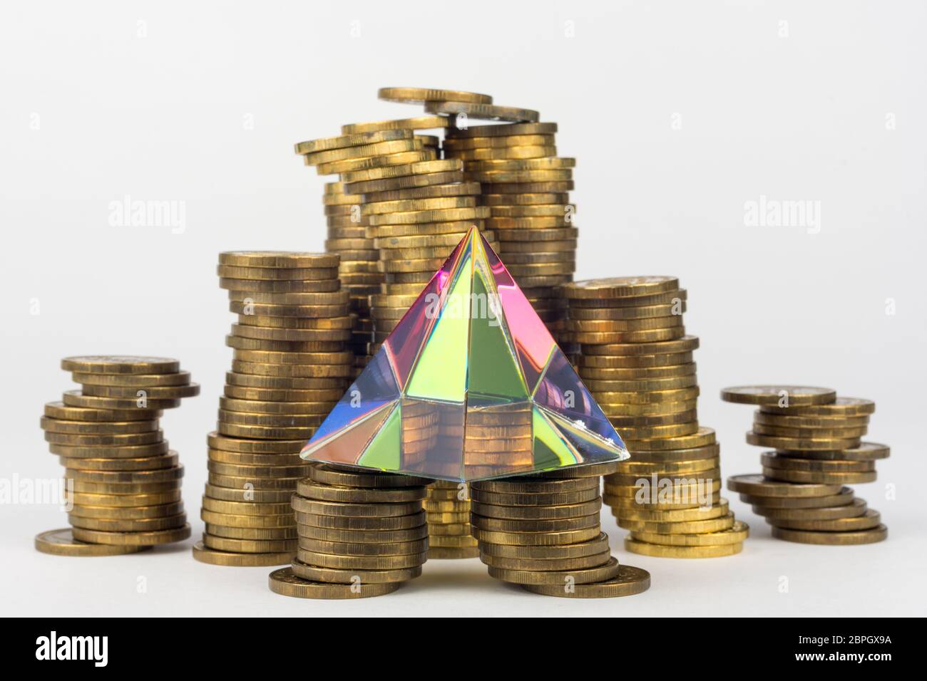 Glass pyramid stands on stacks of coins Stock Photo - Alamy