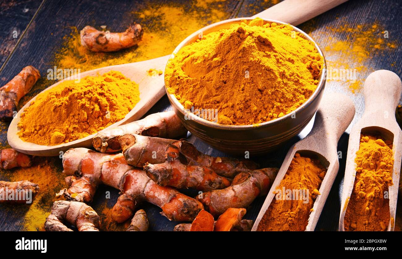 Composition with bowl of turmeric powder on wooden table Stock Photo ...