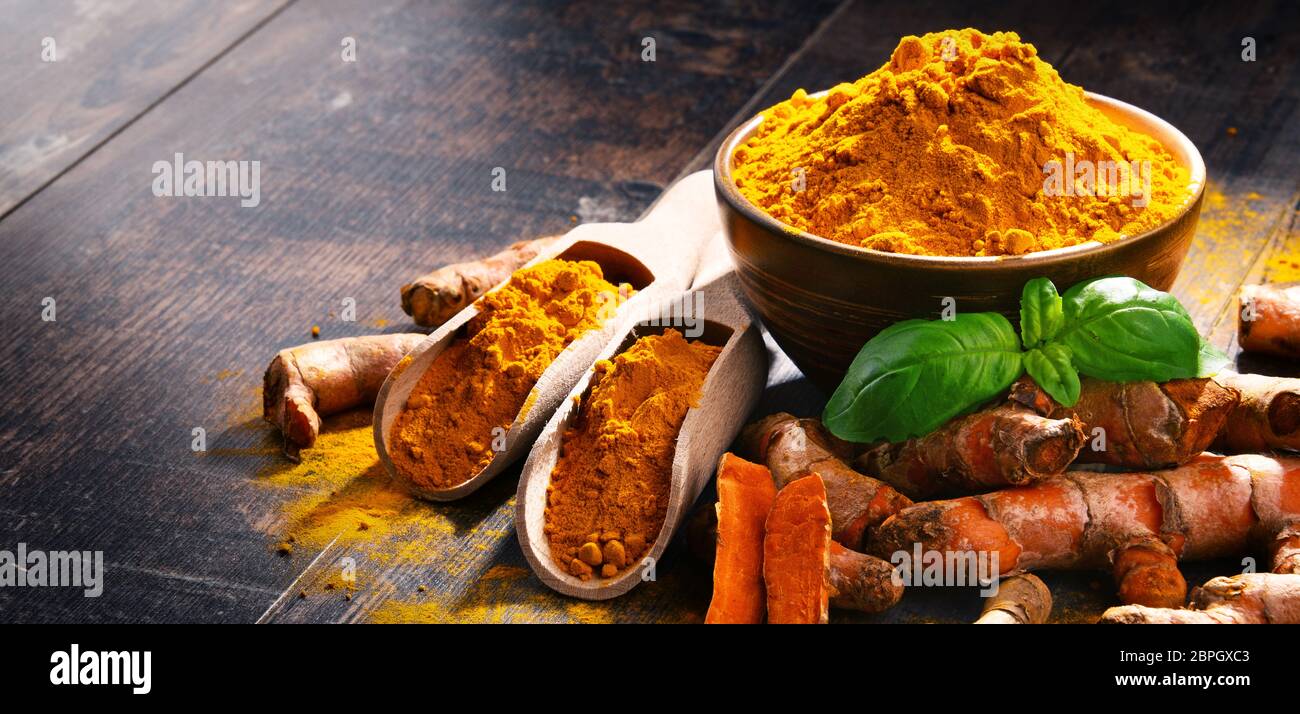 Composition with bowl of turmeric powder on wooden table Stock Photo ...