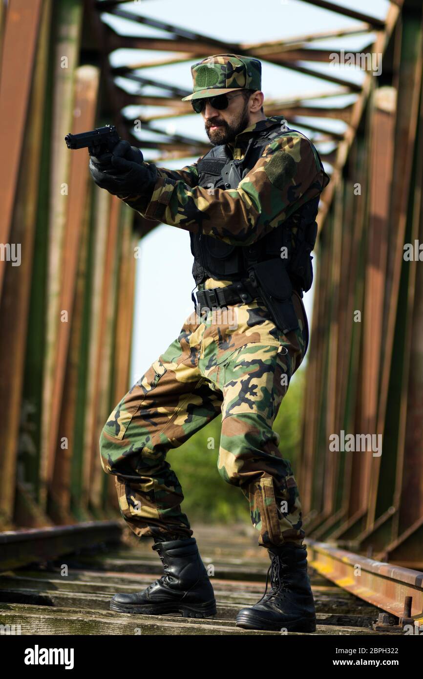 The soldier in military uniform is standing on the railway bridge and ...