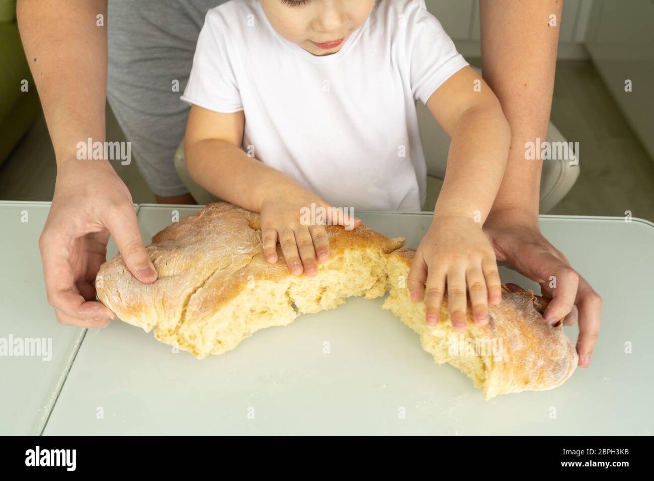 dad and child are breaking freshly baked white bread. family values ...