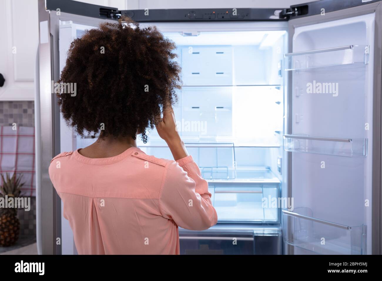 Rear View Of Worried Woman Looking At Empty Refrigerator In Kitchen ...