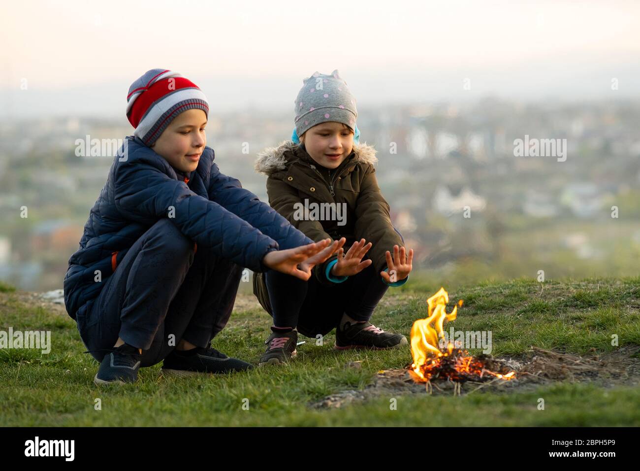 Two children playing with fire outdoors in cold weather Stock Photo - Alamy