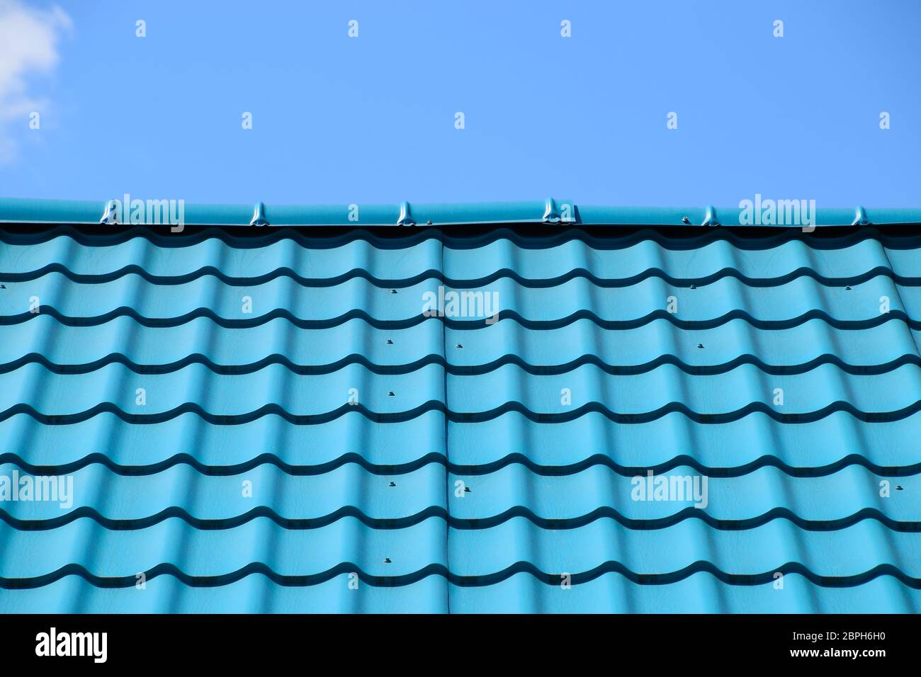 Turquoise metal tiles on the roof of the house. Modern roofing ...