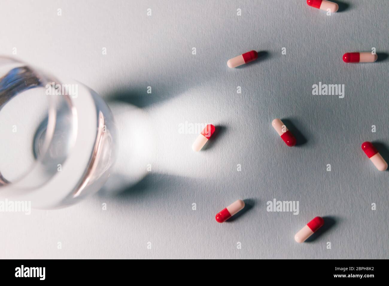 Glass of water, drugs pills capsules on blue background top view ...