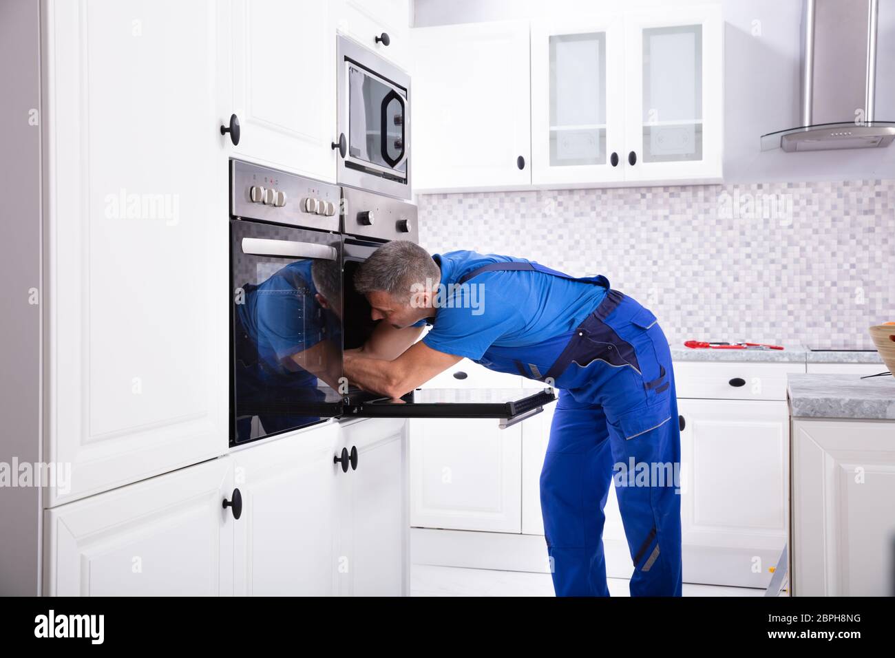 Mature repairman installing kitchen hi-res stock photography and images ...