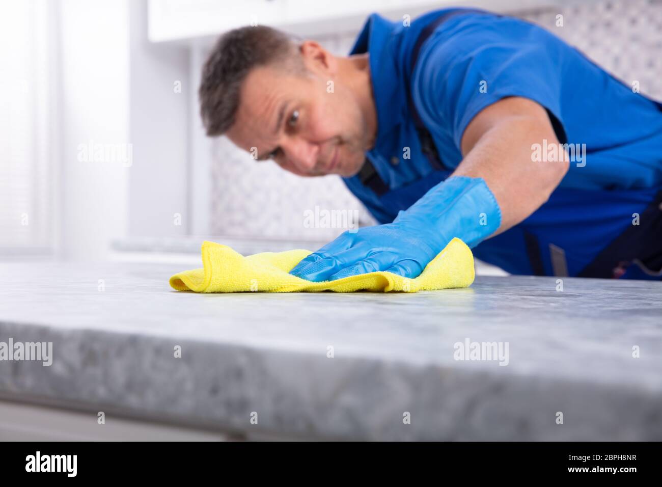 Mid Section Of A Male Janitor Cleaning Dirty Kitchen Counter With Spray ...