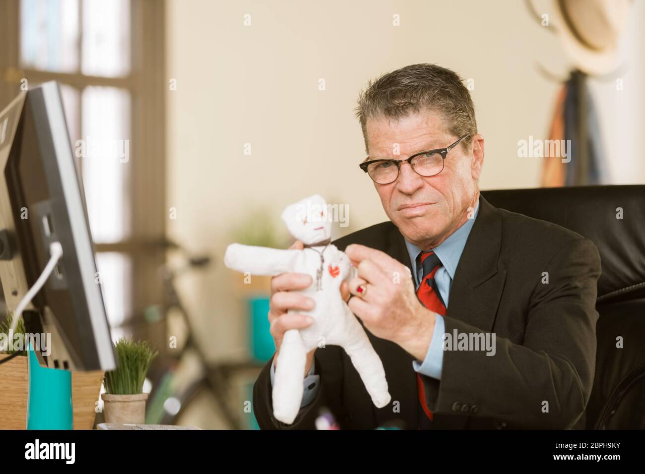 Angry professional man putting a pin into the heart of a Voodoo doll ...