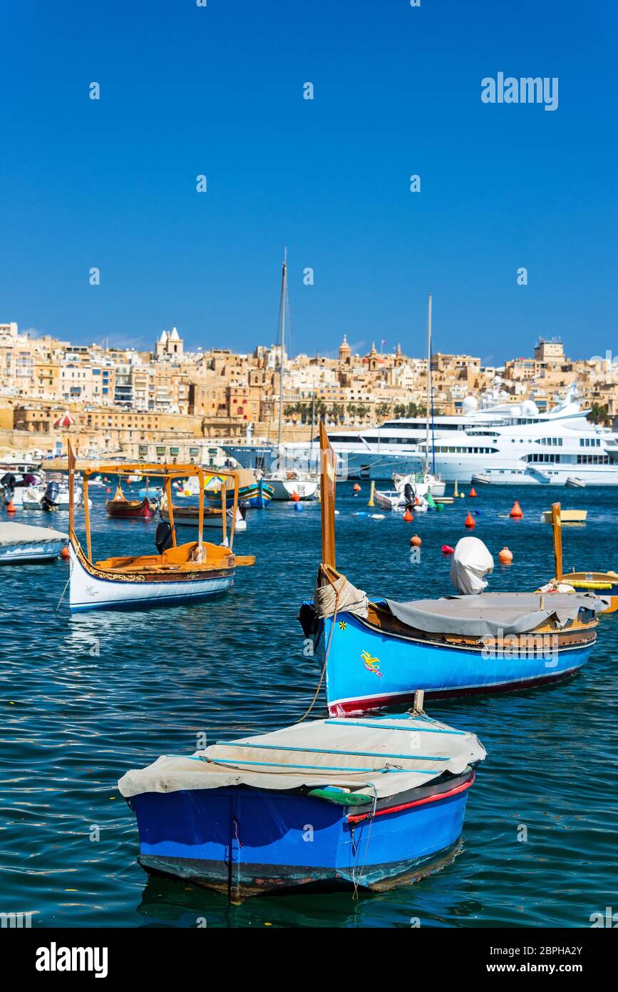 Traditional Maltese boats with superyachts in the background with ...