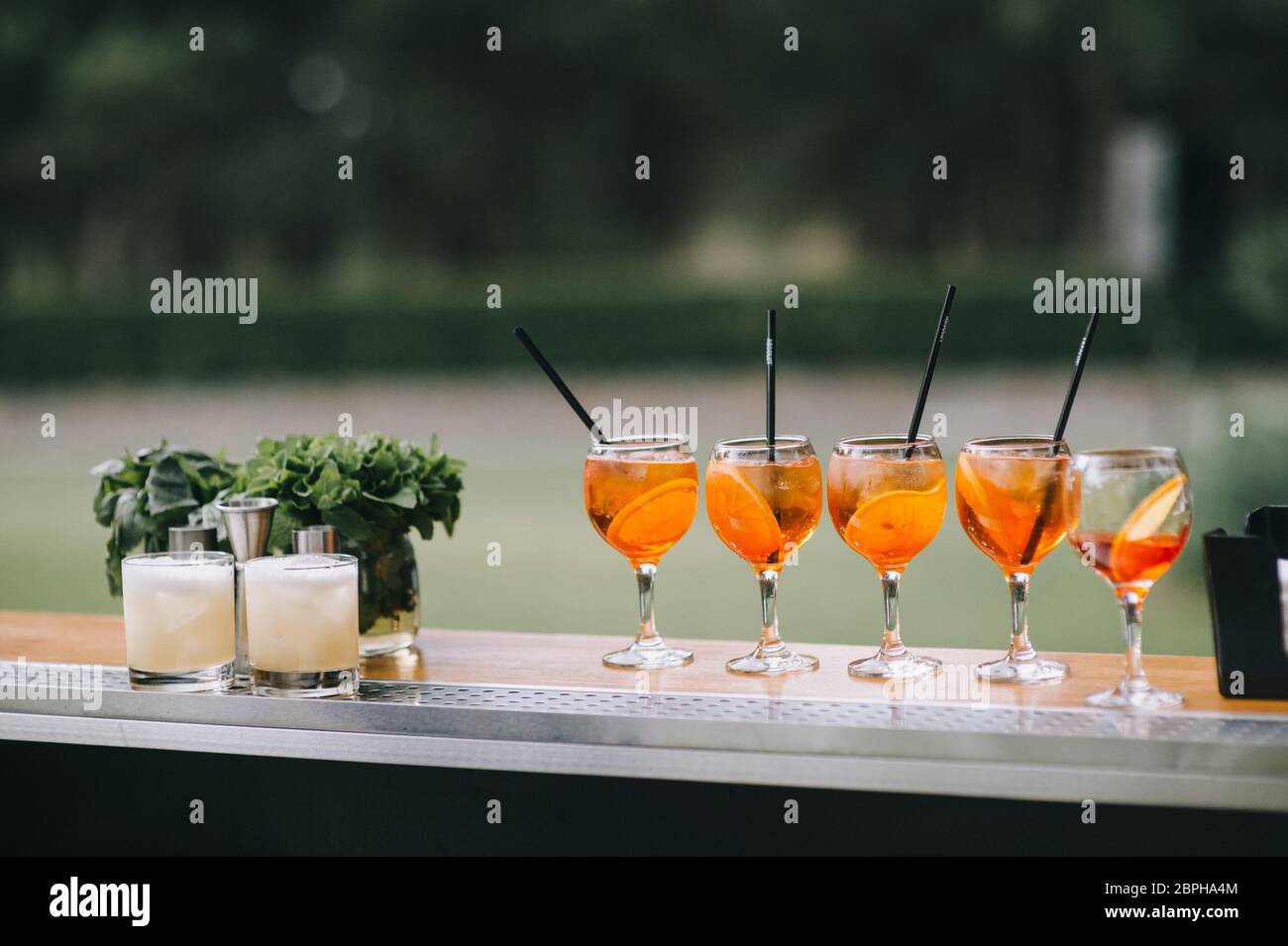 Four glasses of aperol spritz with a straw for cocktails stand on a bar ...