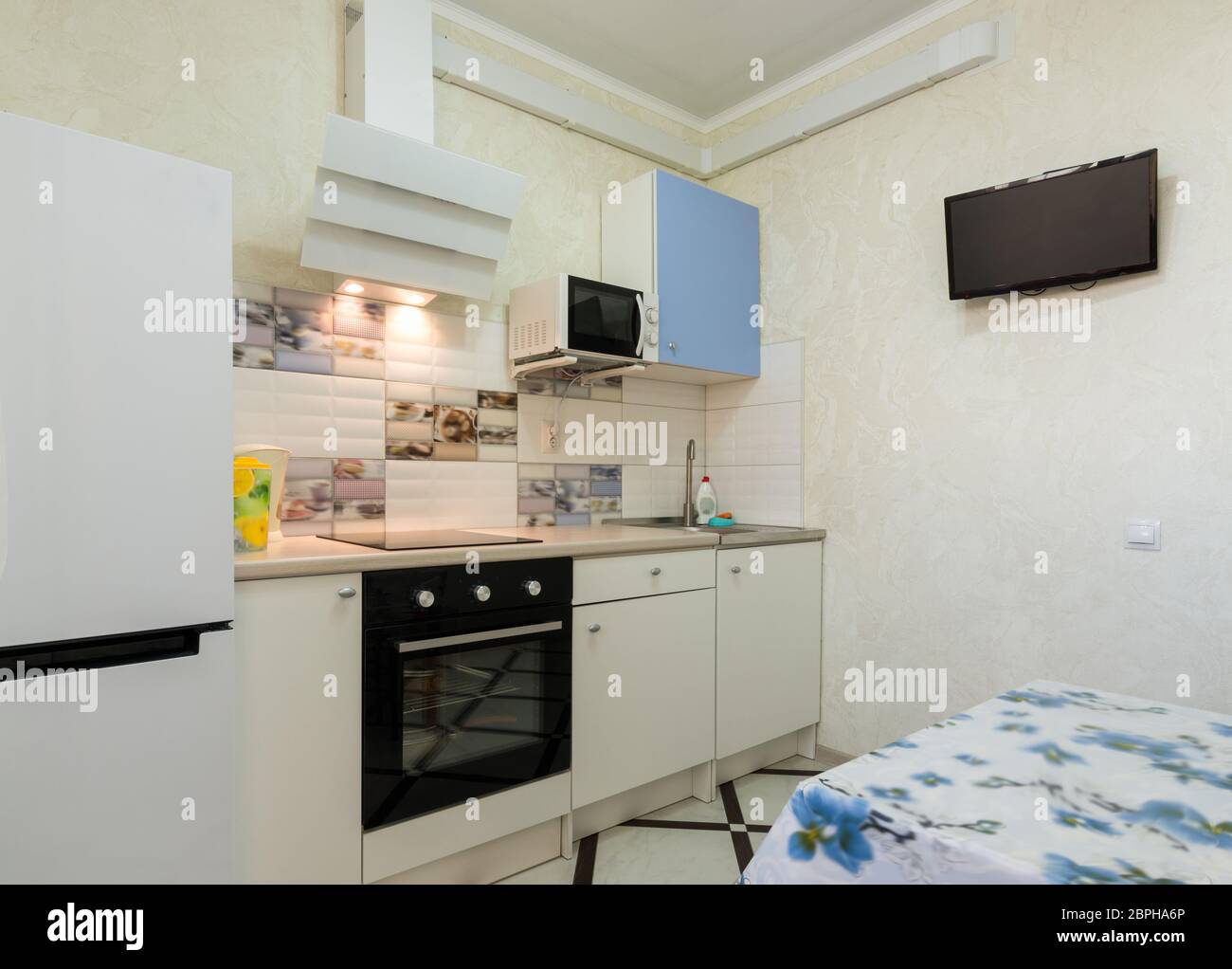 The interior of a small kitchen with a TV on the wall Stock Photo - Alamy