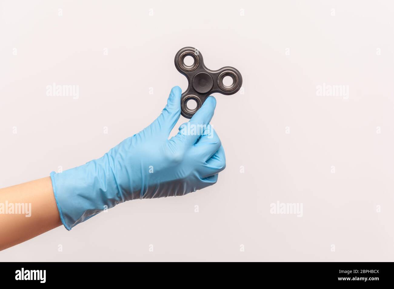 Profile side view closeup of human hand in blue surgical gloves holding ...