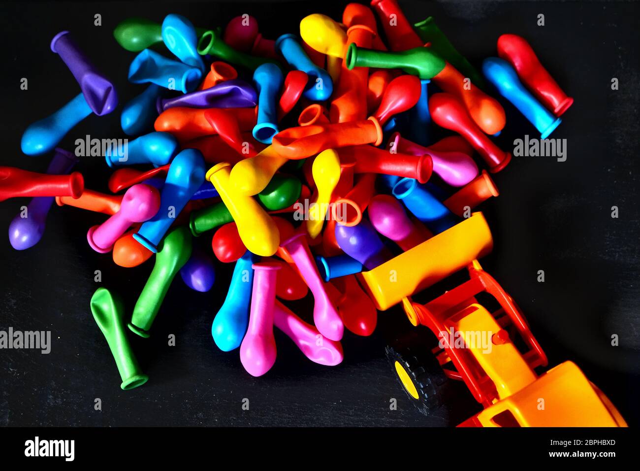 Colorful empty waterballons pushed away by toy front-end loader Stock ...