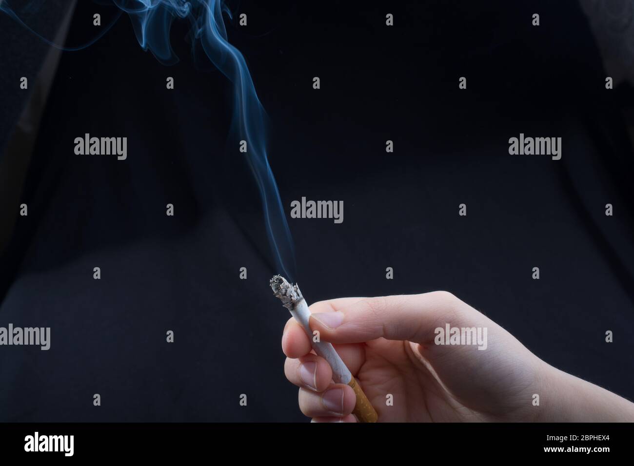 Hand is holding smoking cigarette with smoke around Stock Photo - Alamy