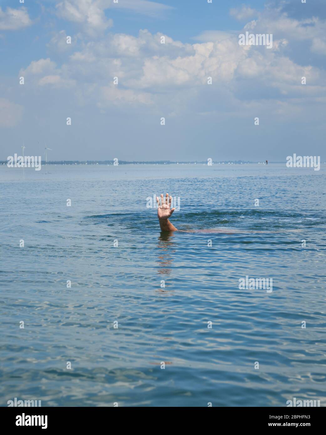right man's hand sticks out from the water in the middle of the ocean ...