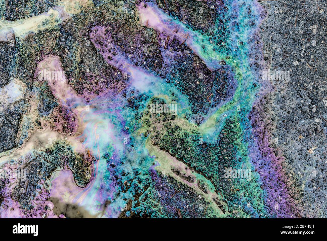 Oily puddles in tire tracks left by an all terrain vehicle on a gravel ...