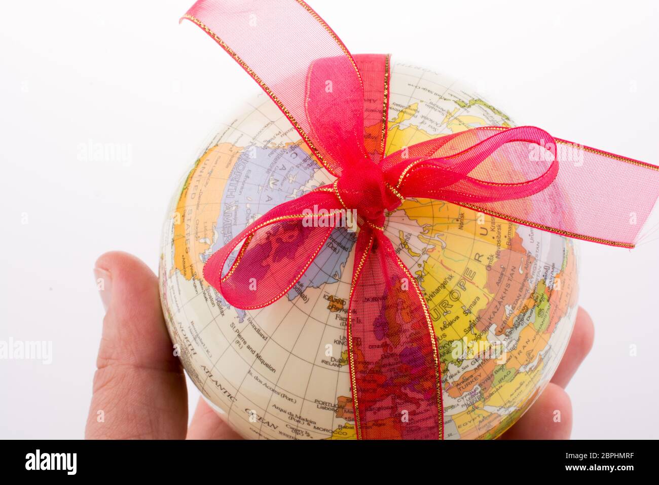 Globe tied with red ribbon on a white background Stock Photo - Alamy