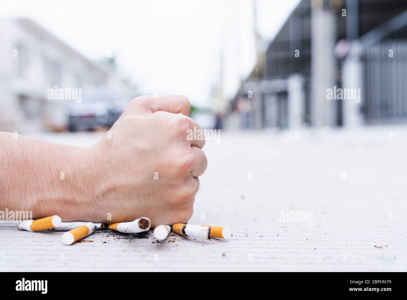 Stop smoking. Close up of male hand breaking cigarette with his fist in ...