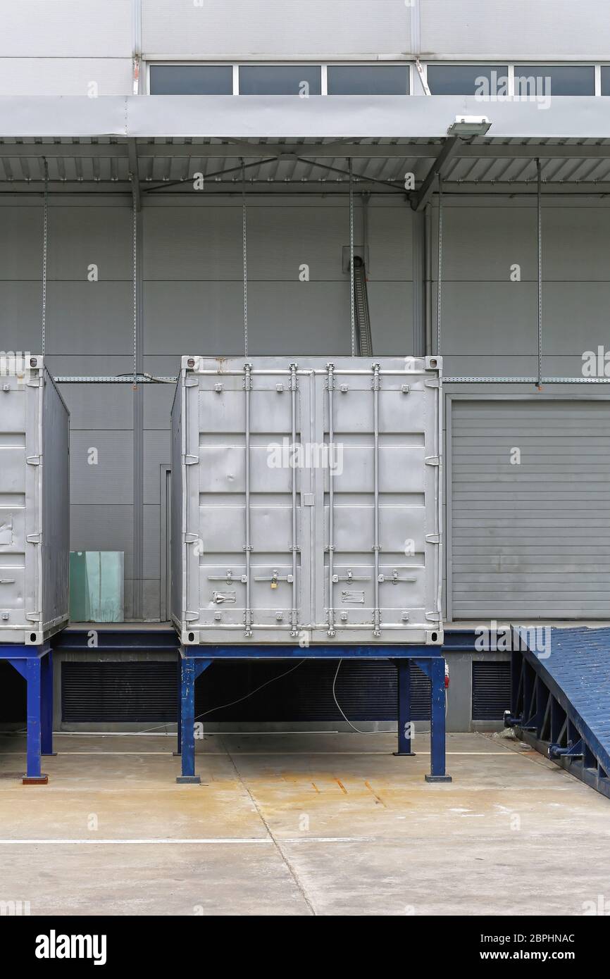 Silver Shipping Container With Leg Support in Front of Warehouse Stock ...
