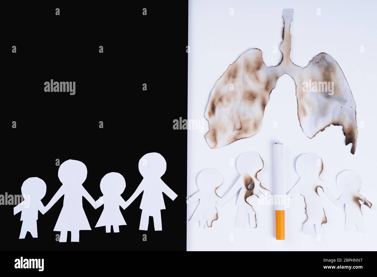 Paper cut of family members destroyed by cigarette on black and white ...