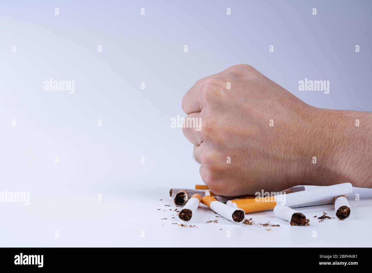 Stop smoking. Close up of male hand breaking cigarette with his fist ...