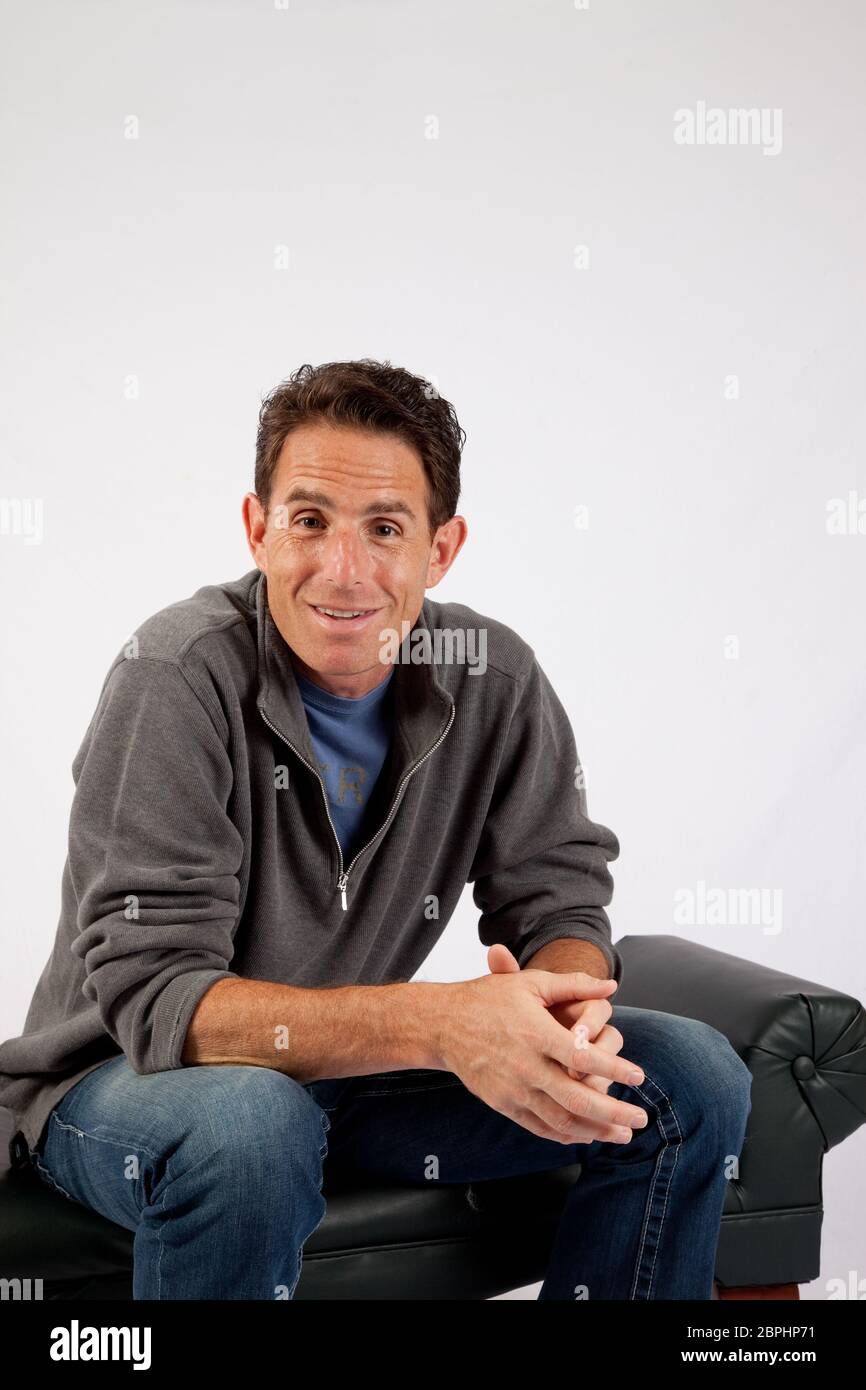 Happy man in grey shirt sitting with a smile Stock Photo - Alamy