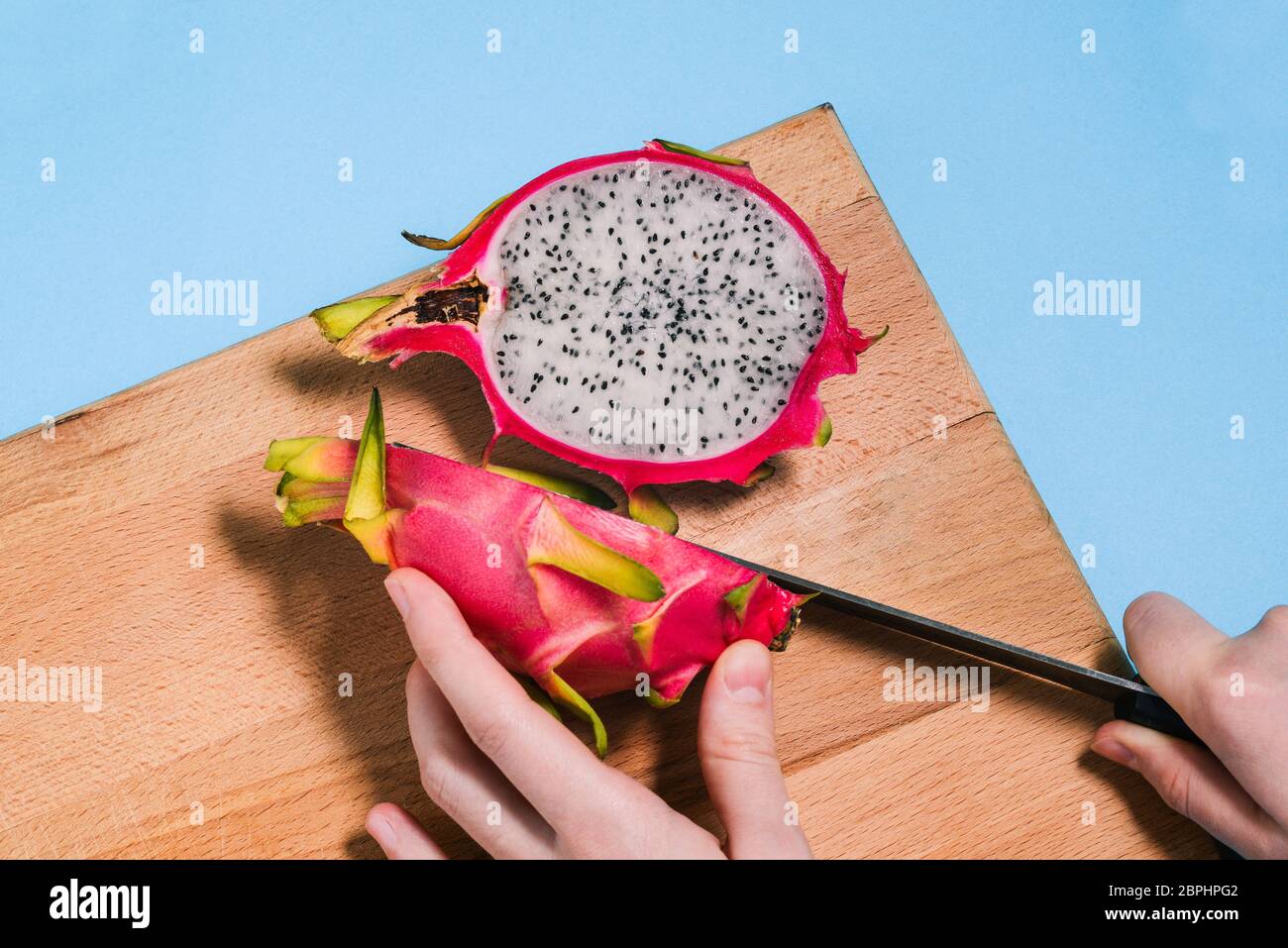 Cut pitaya fruit. Close-up of female hands cutting summer dragon fruit ...