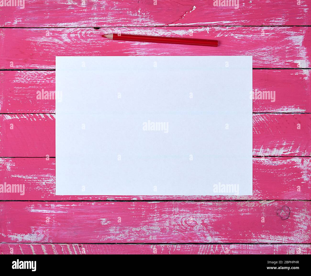 empty white rectangular sheet of paper and red wooden pencil on pink ...