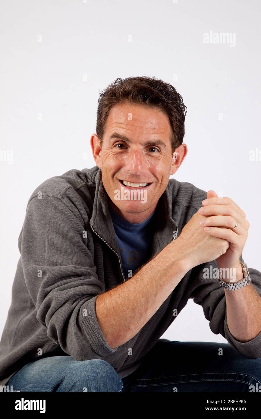 Happy man in grey shirt sitting with a smile Stock Photo - Alamy