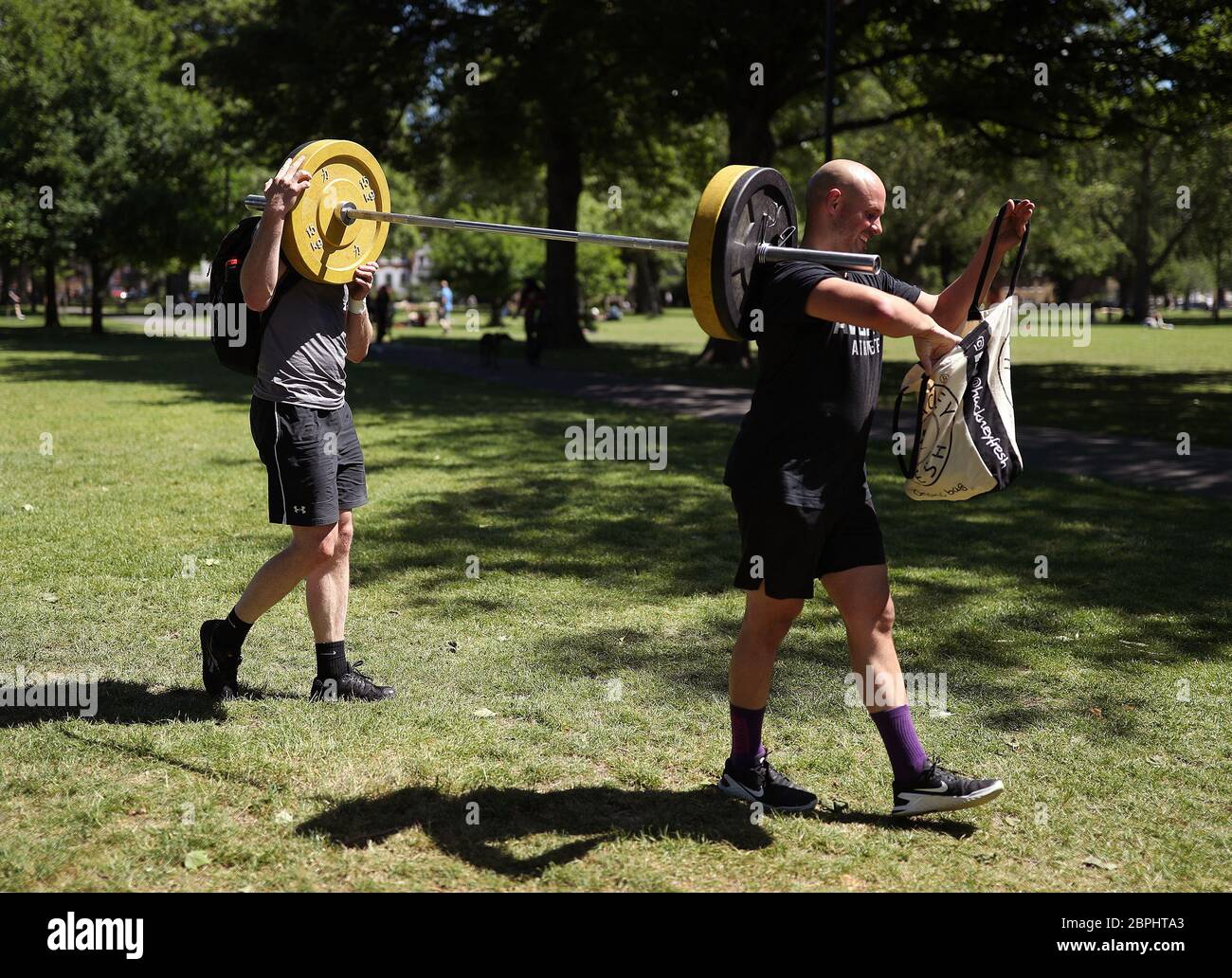 Two men carry 50kgs weights in the hot weather hi-res stock photography ...
