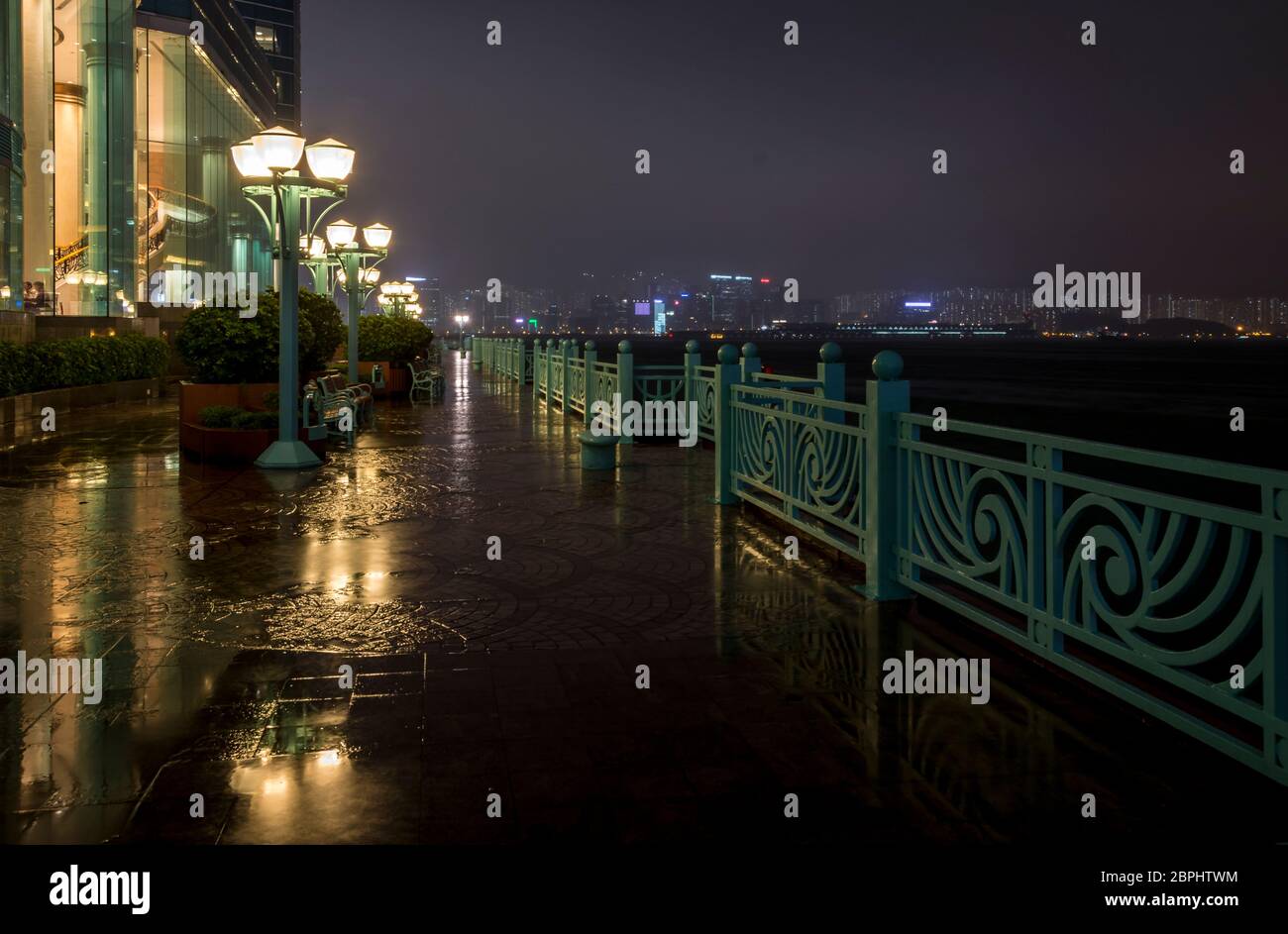 Wet harbour side walkway lined with lamps and Benches at Night Stock ...