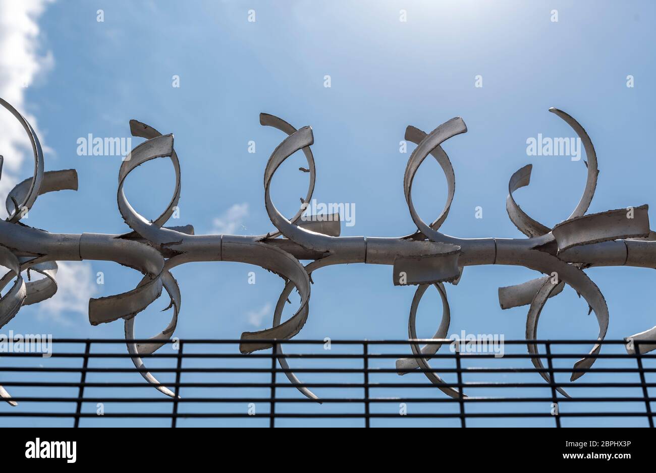 large barbed wire on top of a metal fence Stock Photo - Alamy
