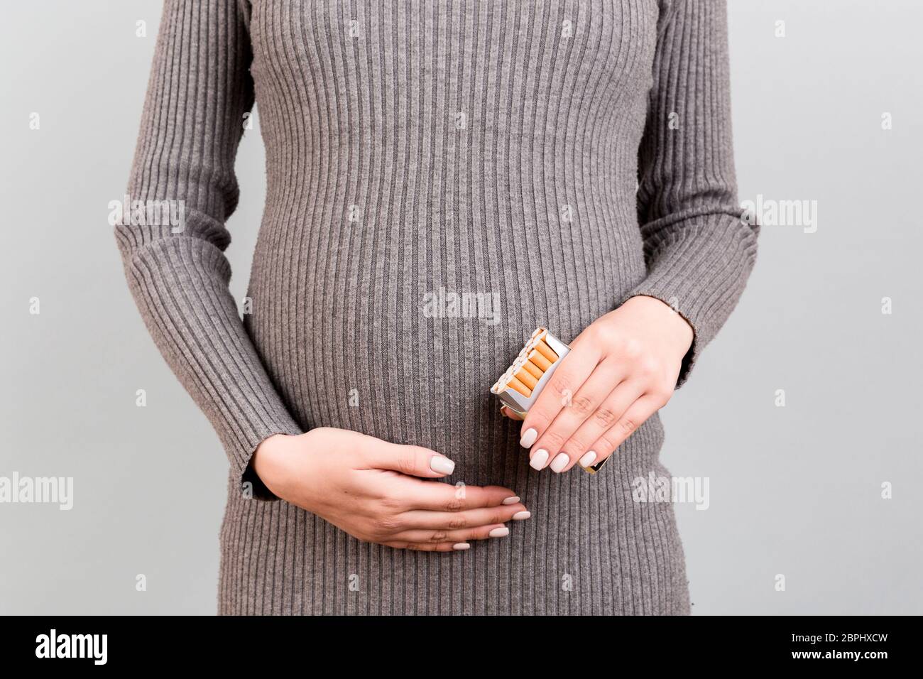 Close up of a pack of cigarettes in pregnant woman's hands at gray ...