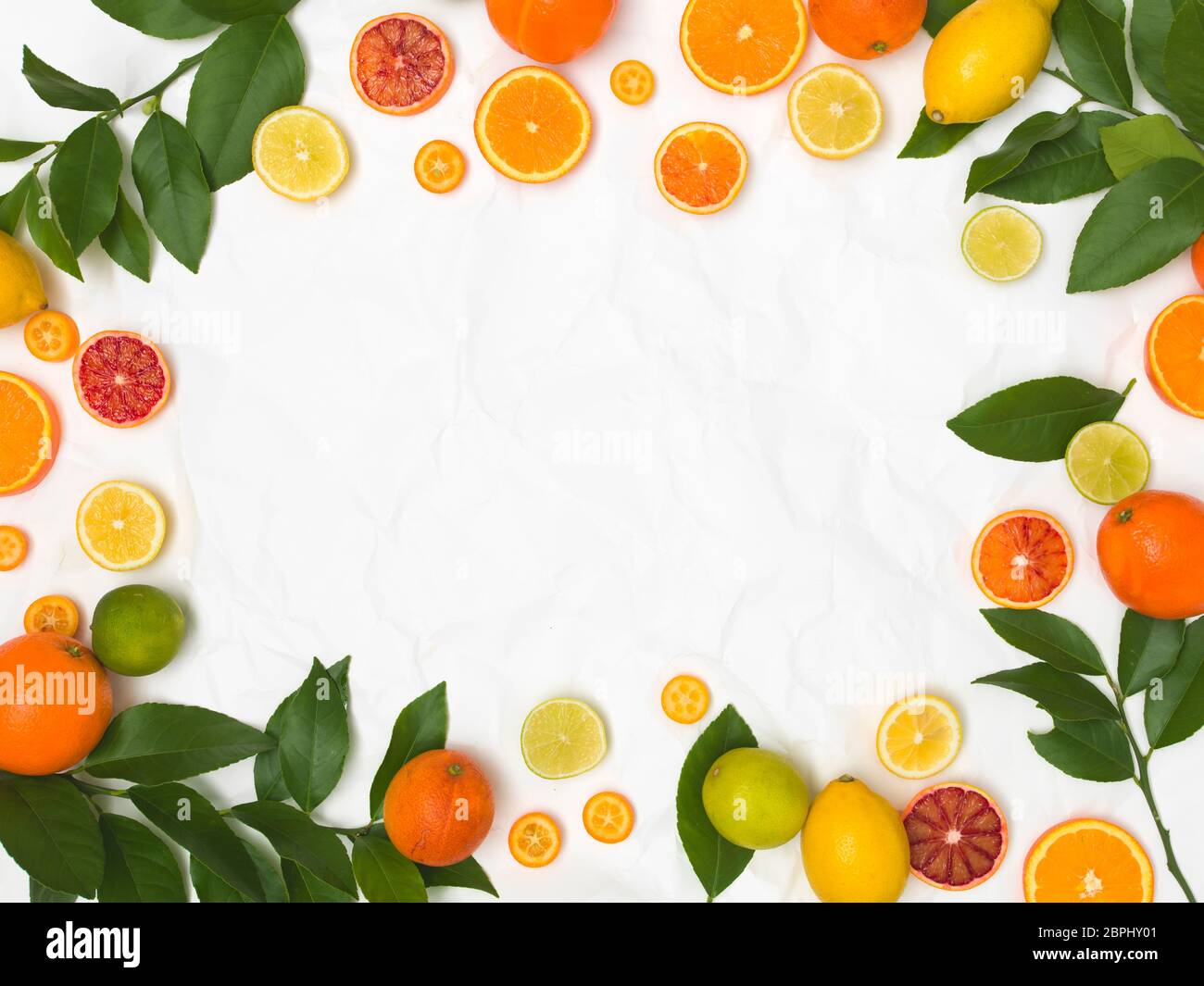 many different fresh citrus fruits on white crumpled paper background ...