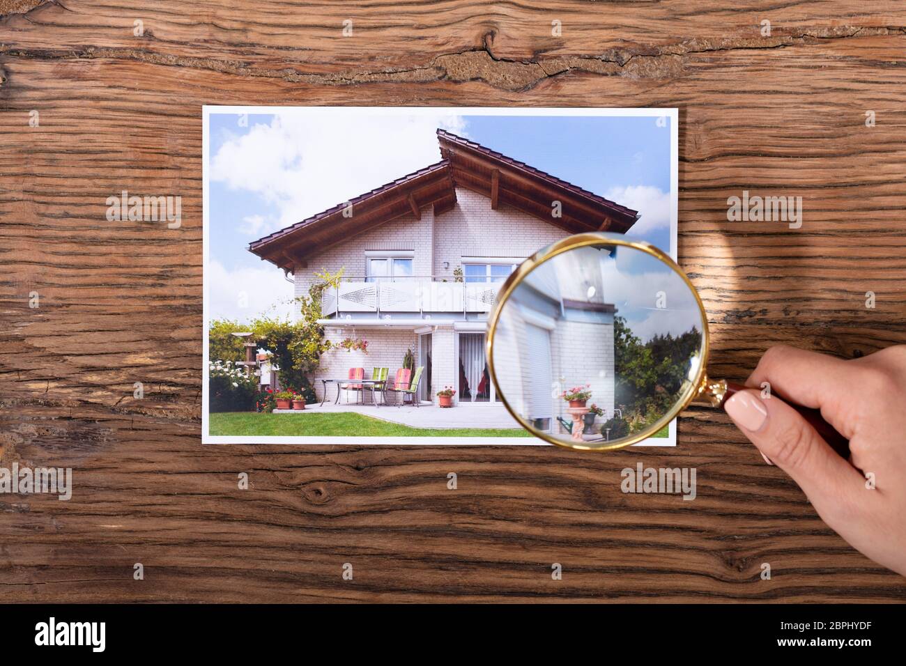 Close-up Of A Person Holding Magnifying Glass Over The House Photograph ...
