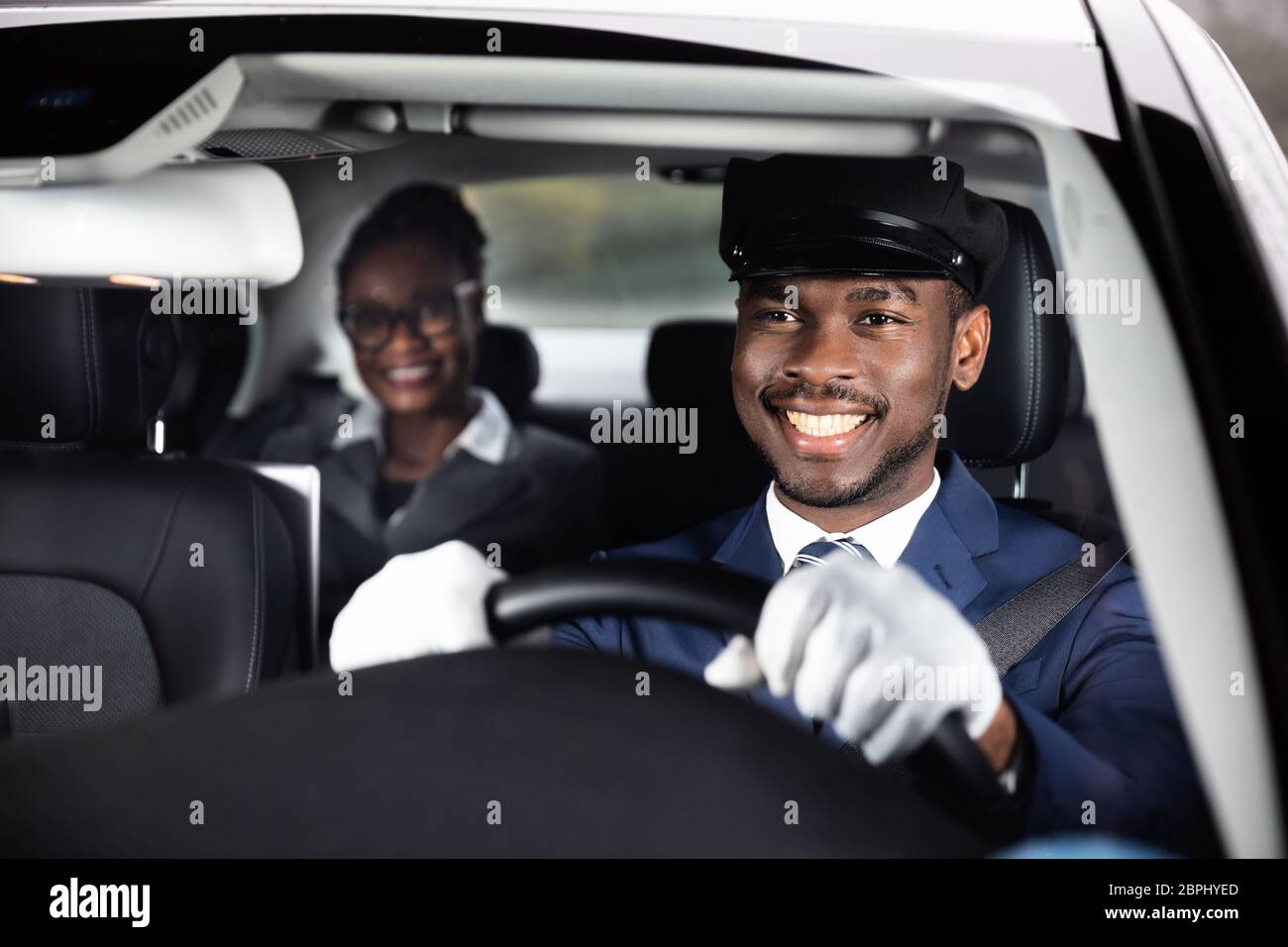 Businesswoman Sitting Behind Happy African Male Chauffeur Driving Car ...