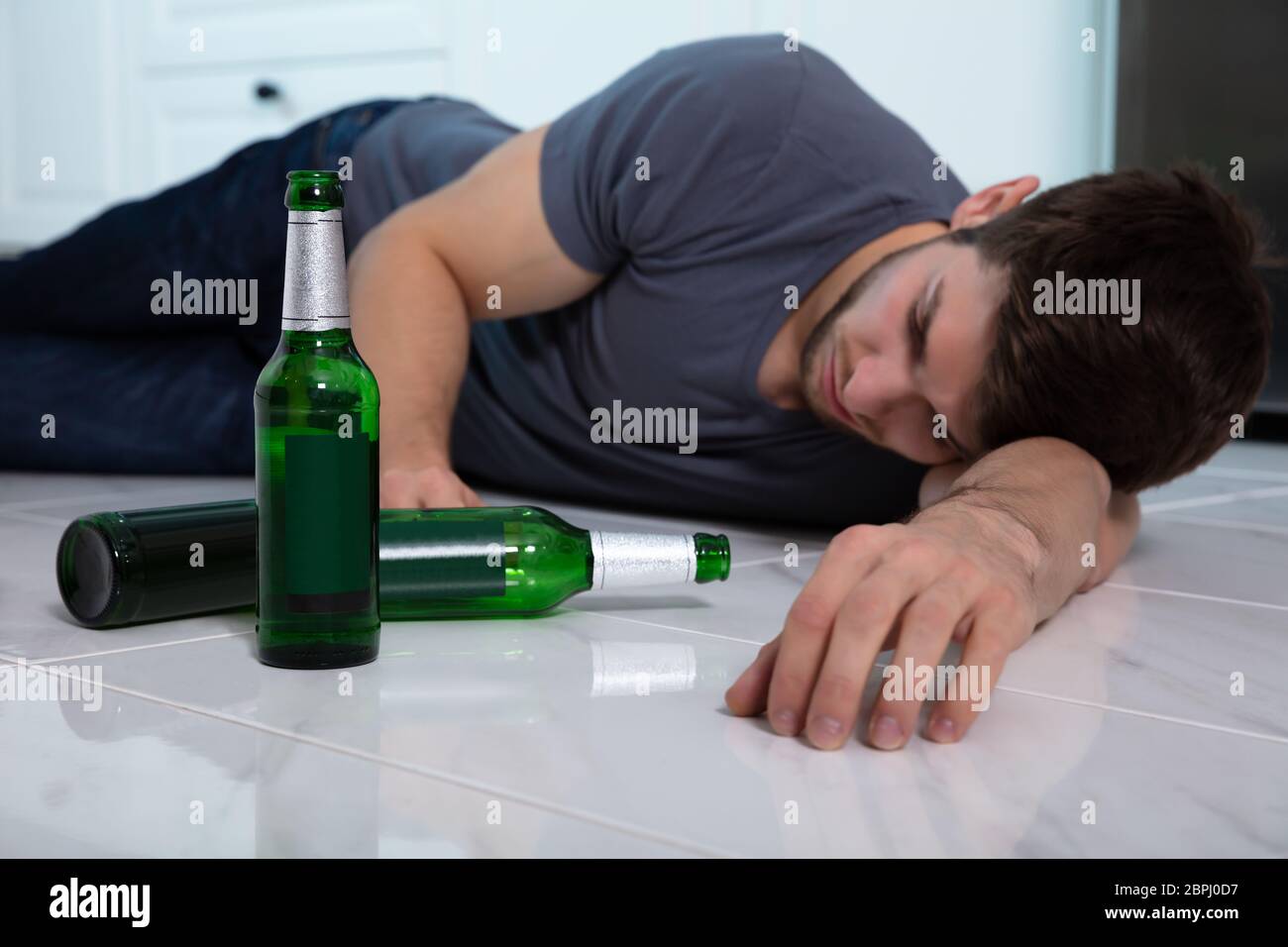 Alcoholic Man Lying On Floor With Beer Bottles In Kitchen Stock Photo ...