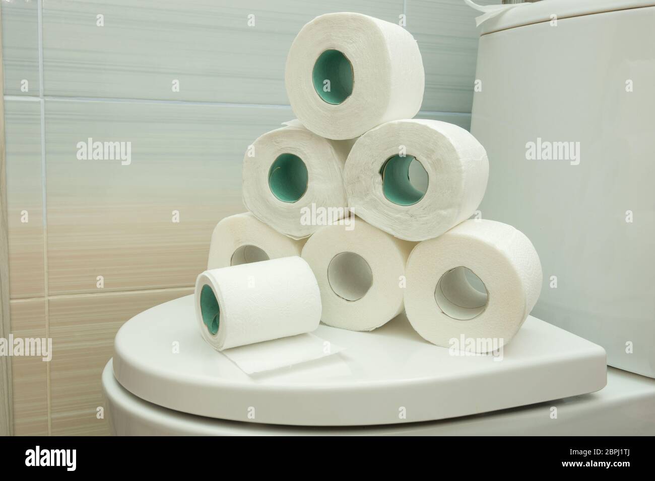 The pyramid of toilet rolls lies on the lid of the toilet bowl Stock ...