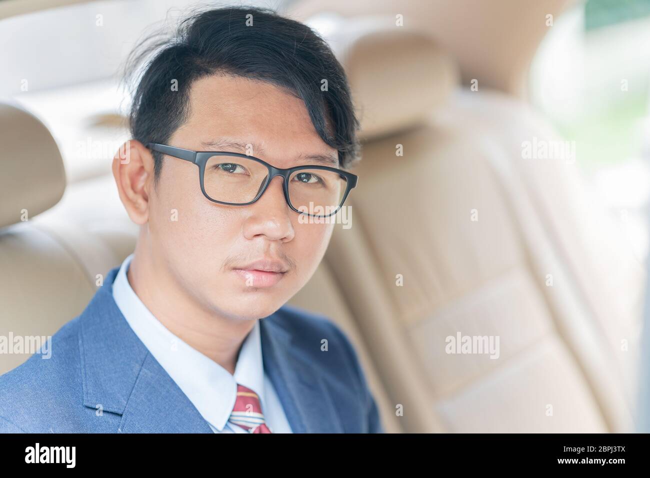 Young asian business men portrait in suit sit in the backseat of a car ...