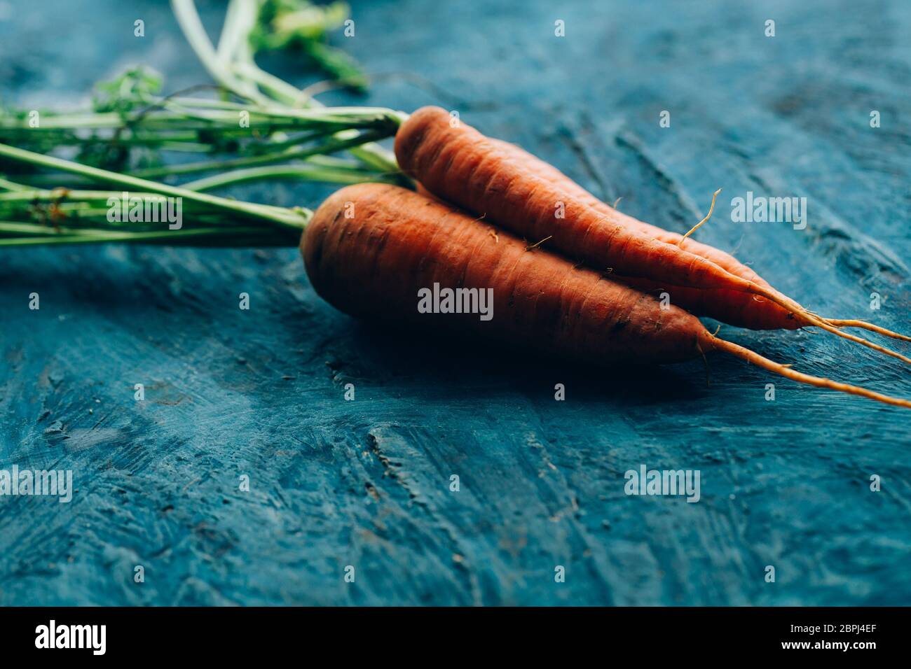 Fresh carrots on a blue wooden background Stock Photo - Alamy
