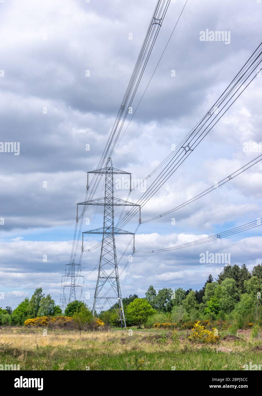Tall electricity pylons in a rural farmland setting in a line crossing ...