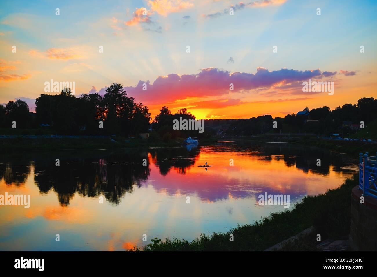 Sunset over the river. Bright colorful sky with clouds reflected in the ...