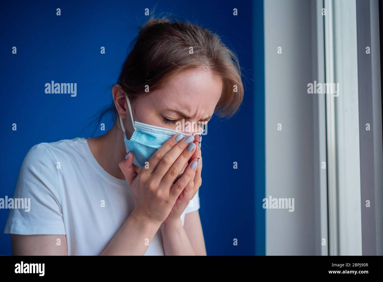 Woman wearing face mask, feeling sick, suffering from sneezing, looking ...