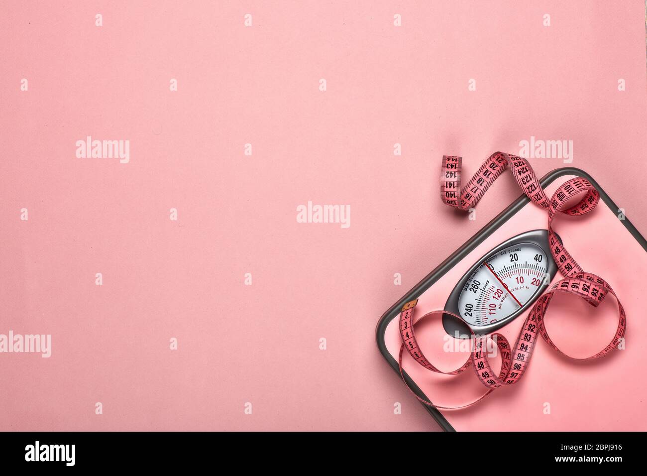 Female fitness still life. Scales and measuring tape on pink background ...