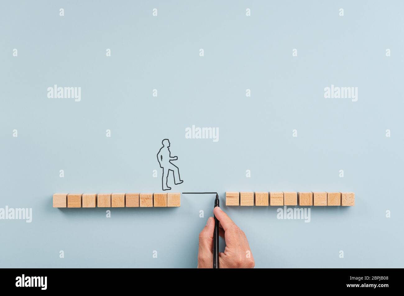 Male hand drawing a bridge between two rows of wooden blocks for a ...